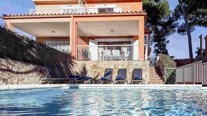 Hotel com piscina, espreguiçadeiras e fachada de pedra.