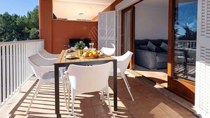 Uma varanda com uma mesa de jantar, cadeiras e churrasqueira.