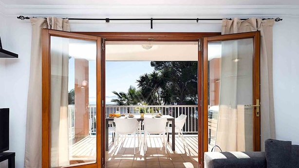 Quarto com porta de vidro deslizante que dá para um pátio externo com mesa e cadeiras.