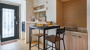 Uma cozinha compacta com área de jantar, pia e porta que dá para uma varanda.