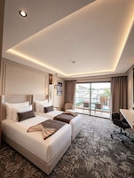 Quarto de hotel com uma cama grande, uma escrivaninha e vista para o exterior.