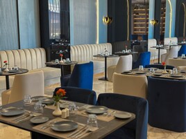 Um restaurante com cabines e mesas, algumas com cadeiras azuis, e um design de interiores moderno.