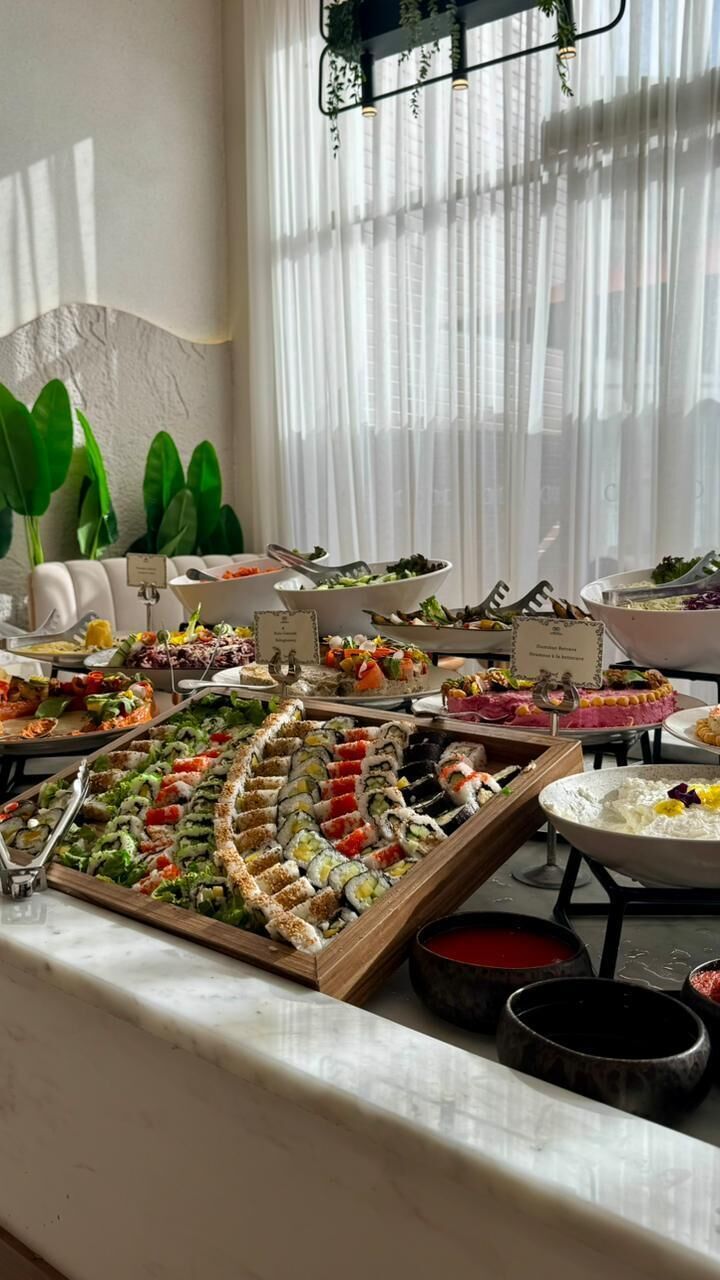 Buffet com diversos alimentos e uma planta decorativa.