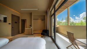 Quarto de hotel moderno com uma janela grande, uma cama, uma escrivaninha e uma cadeira.