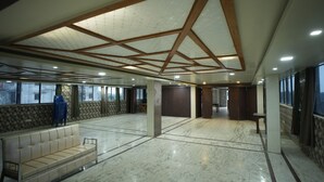 Um espaço interno amplo com piso de mármore, um sofá e um banco.