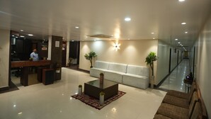 Um hall moderno com uma receção, um sofá, uma mesa de centro e uma escadaria.