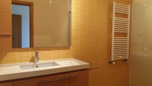 Um banheiro com pia, espelho e porta-toalhas.