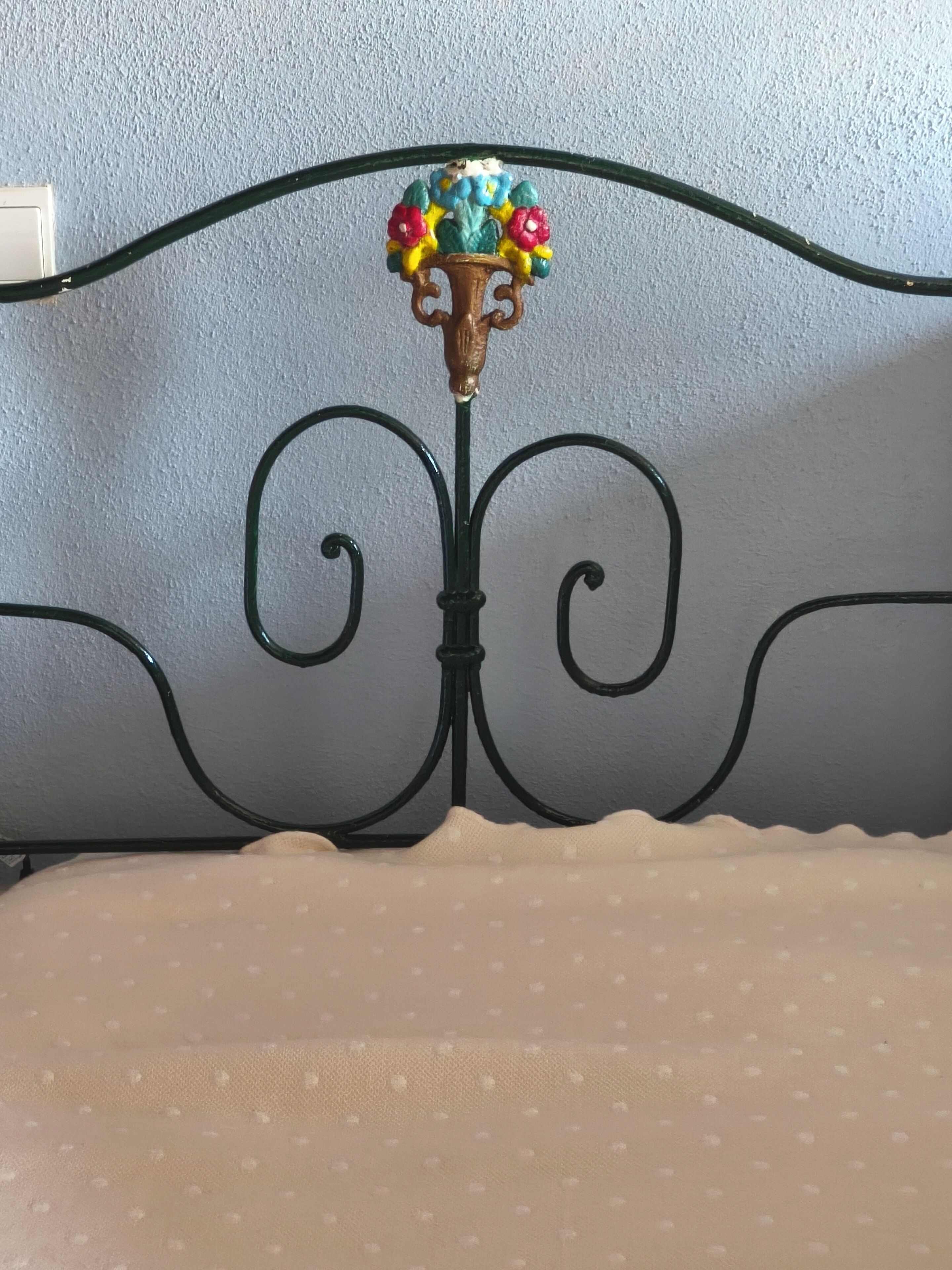 Uma cama com cabeceira de metal e um motivo floral decorativo.