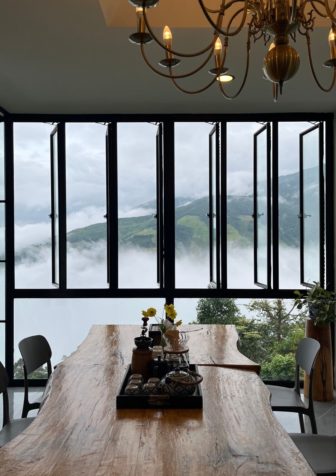 Mesa de jantar com vista para montanhas e nuvens através de grandes janelas.
