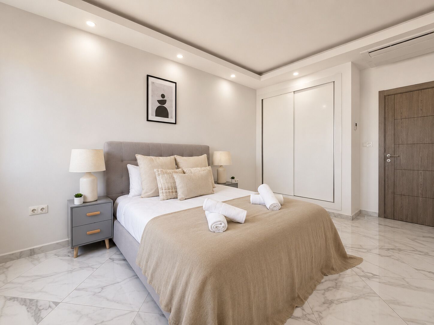 Quarto moderno com cama, mesas de cabeceira, um quadro emoldurado, guarda-roupa e uma porta.