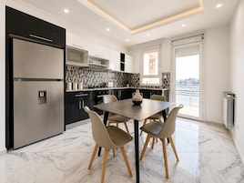 Cozinha moderna com área de refeições, incluindo geladeira, micro-ondas, fogão e mesa de jantar com cadeiras.