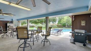 Um pátio externo com piscina, área de churrasco e espaço para sentar.
