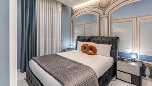 Quarto com uma cama grande, mesa de cabeceira, abajur e vista para o mar pela janela.