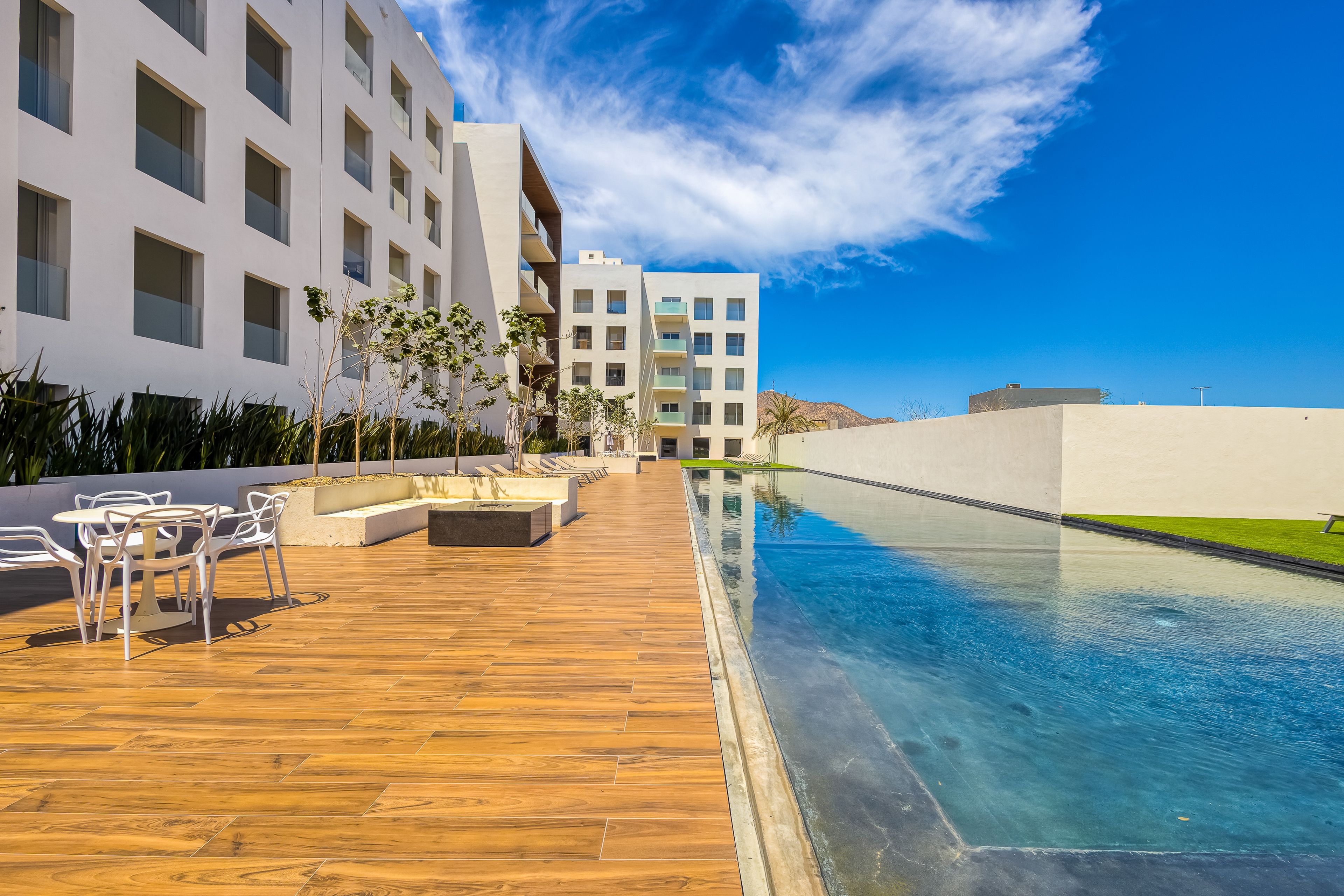 Um hotel moderno com área de piscina, espaço para sentar ao ar livre e vista para as montanhas.