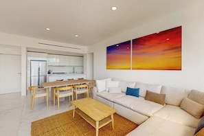 Uma sala de estar moderna com sofá, mesa de centro e área de jantar.