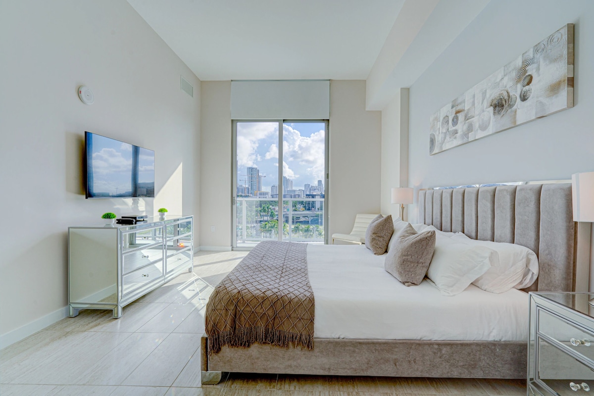 Quarto moderno com uma cama grande, TV, vista da cidade e design minimalista.