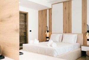 Quarto de hotel moderno com uma cama grande, paredes de painel de madeira e uma mesa de cabeceira com abajur.