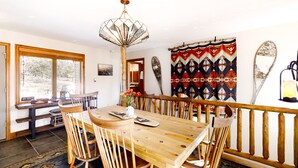 Uma área de refeições com uma mesa e cadeiras de madeira, um candelabro e vista para o exterior.