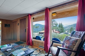 Um quarto com uma janela grande, uma porta de madeira e uma cadeira com almofada.