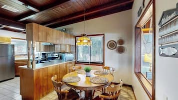 Uma cozinha com armários de madeira, uma ilha central e uma área de jantar com mesa redonda e cadeiras.