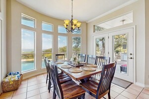 Uma sala de jantar com uma mesa grande, cadeiras e um lustre.