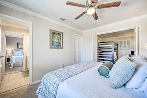 Quarto com cama, ventilador de teto, um quadro e closet espaçoso.