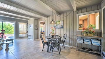 Um quarto amplo com uma mesa de jantar e cadeiras, um lustre pendente e vista para o exterior.