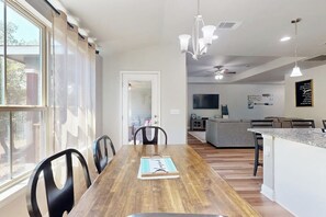 Uma cozinha moderna com uma ilha central, uma área de refeições com mesa de madeira e vista através de amplas janelas.