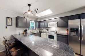 Uma cozinha moderna com bancadas de granito, eletrodomésticos de aço inoxidável e um claraboia.