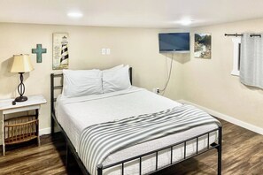 Quarto com cama, mesa de cabeceira, luminária, televisão e decorações nas paredes.