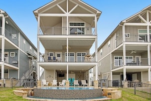 Um edifício residencial com várias andares, varandas, piscina e áreas de estar ao ar livre.