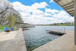 Um cais que se estende por um lago calmo, rodeado por cadeiras e uma área coberta.
