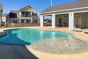 Piscina com fonte, rodeada por um espaço coberto com espreguiçadeiras.