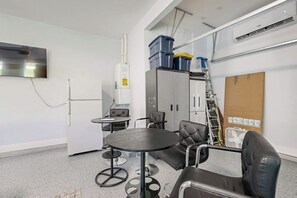 Um espaço de escritório moderno com uma mesa redonda, cadeiras de couro, um quadro branco e armários de armazenamento.
