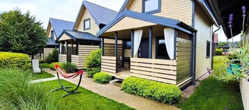 Uma fileira de casas de férias modernas, com dois andares, varandas cobertas e um jardim bem cuidado.