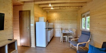 Interior de uma cabana de madeira com cozinha, sala de jantar e área de estar.