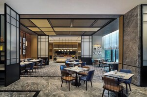 Um restaurante moderno com um balcão central, várias mesas e cadeiras.