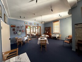 Uma sala de jantar com mesas, cadeiras, um espelho grande e obras de arte nas paredes.