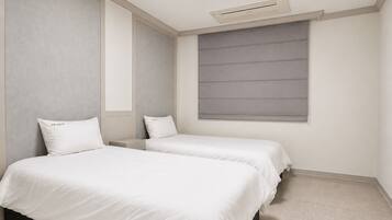 Quarto de hotel moderno com duas camas, uma janela grande com persianas, iluminação no teto e ar condicionado.