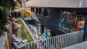Um edifício moderno com telhado plano, janelas amplas e uma varanda com área de estar ao ar livre.