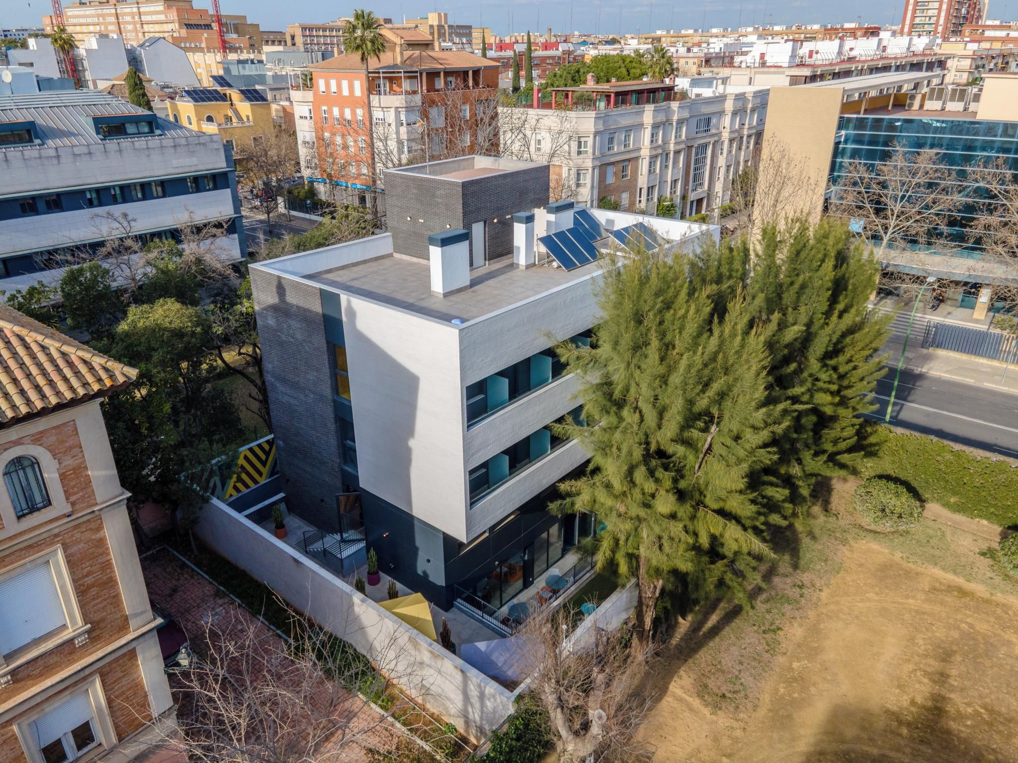Um edifício moderno de vários andares com telhado plano, janelas amplas e painéis solares.