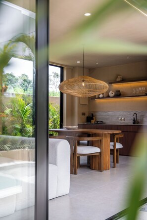Uma cozinha moderna com área de refeições, janelas amplas e um lustre.