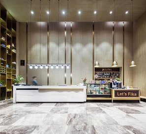 Uma receção com design moderno, uma máquina de café e uma vitrine de vidro.