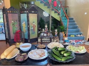 Uma mesa de jantar com diversos pratos, uma escadaria e decorações tradicionais.