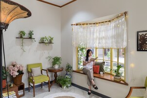 Um recanto acolhedor para leitura, com janela, poltrona, mesinha e estante.