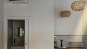 Uma cozinha moderna com armários brancos, forno embutido e luminária pendente.