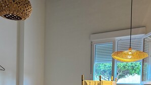 Quarto com cama, mesa de cabeceira, cômoda, janela com persianas e luminária pendente.