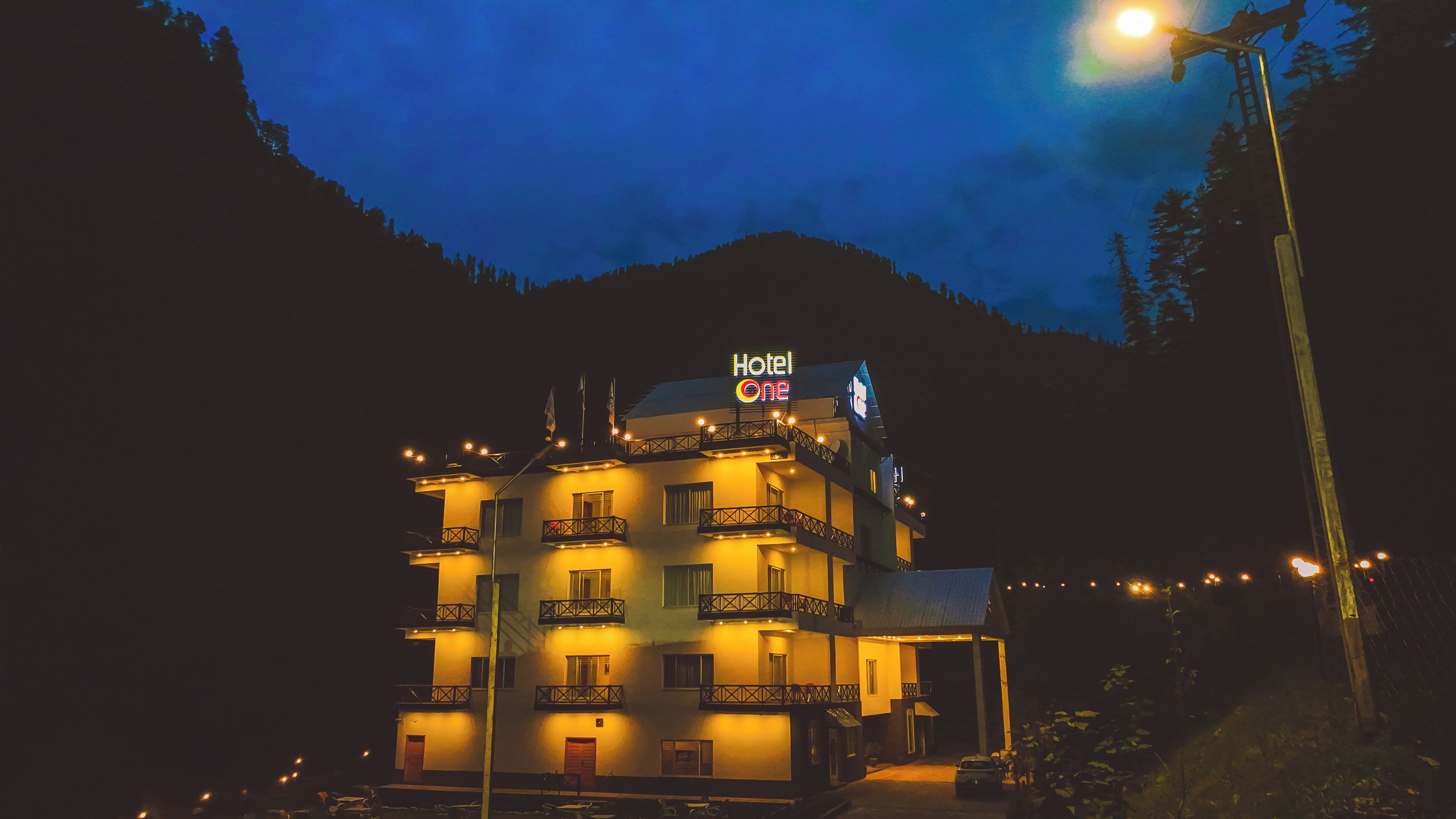 Um hotel de vários andares com varandas, uma bandeira e uma placa com a inscrição 'Hotel One'.