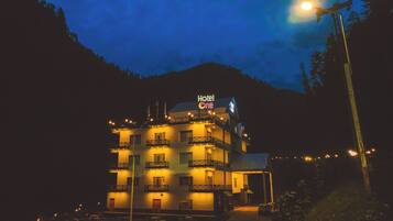 Um hotel de vários andares com varandas, uma bandeira e uma placa com a inscrição 'Hotel One'.