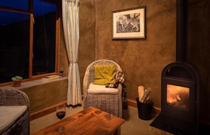 Um quarto acolhedor com uma cadeira de vime, uma mesa com um copo e uma lareira.